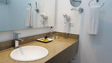 Casa de banho com lavatório, toalheiro, secador de cabelo e espelho.