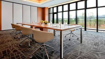 Uma sala de conferências com uma mesa comprida, quatro cadeiras e vista através de grandes janelas.