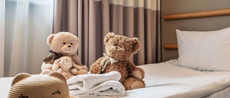 Uma cama com dois ursinhos de pelúcia, um chapéu de palha e uma toalha branca dobrada.