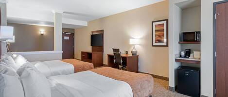 Quarto de hotel com duas camas, uma escrivaninha, uma cadeira, uma televisão, um abajur, um micro-ondas e um frigorífico.
