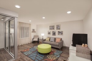 Uma sala de estar moderna com um sofá, um banquinho e uma TV de tela plana.