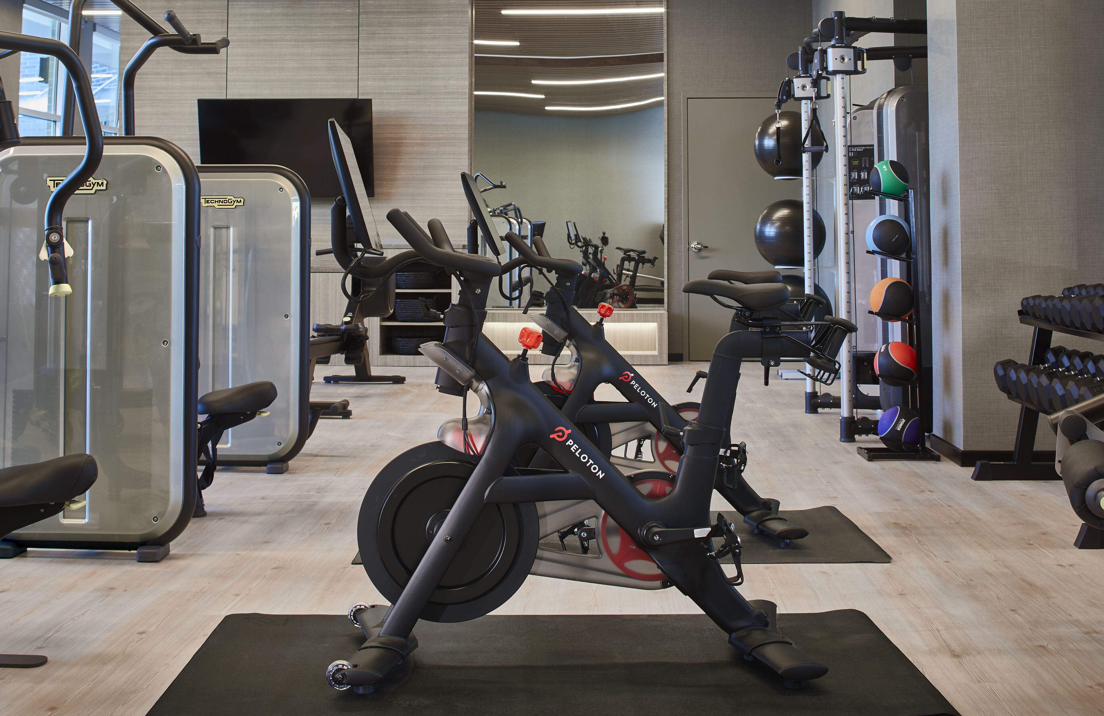 Uma academia com bicicletas ergométricas, máquinas de musculação e bolas de exercício.