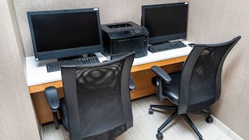 Um espaço de trabalho com dois monitores, uma impressora e duas cadeiras de escritório.