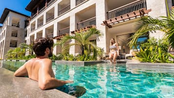 Um homem em uma piscina, com um edifício ao fundo.