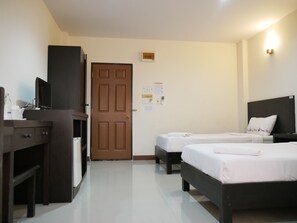 Quarto de hotel com duas camas de solteiro, uma mesa de trabalho com televisão e um guarda-roupa.