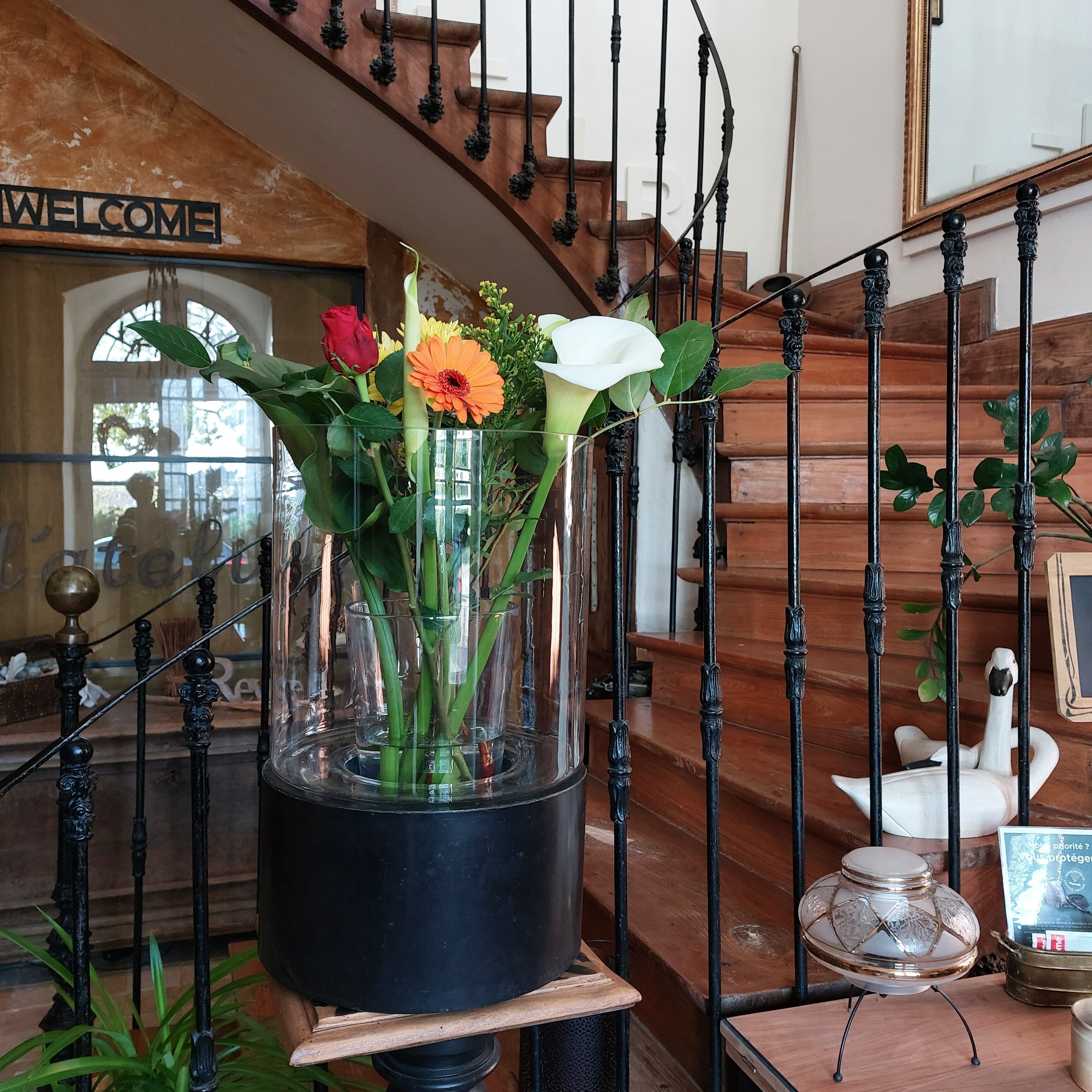 Uma escada com um vaso de flores de vidro sobre um suporte.