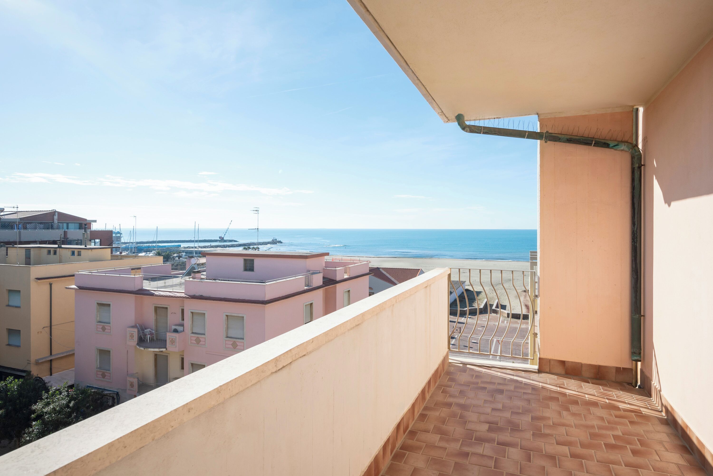 Varanda com vista para o mar, edifícios próximos e céu limpo.