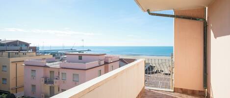 Varanda com vista para o mar, edifícios próximos e céu limpo.