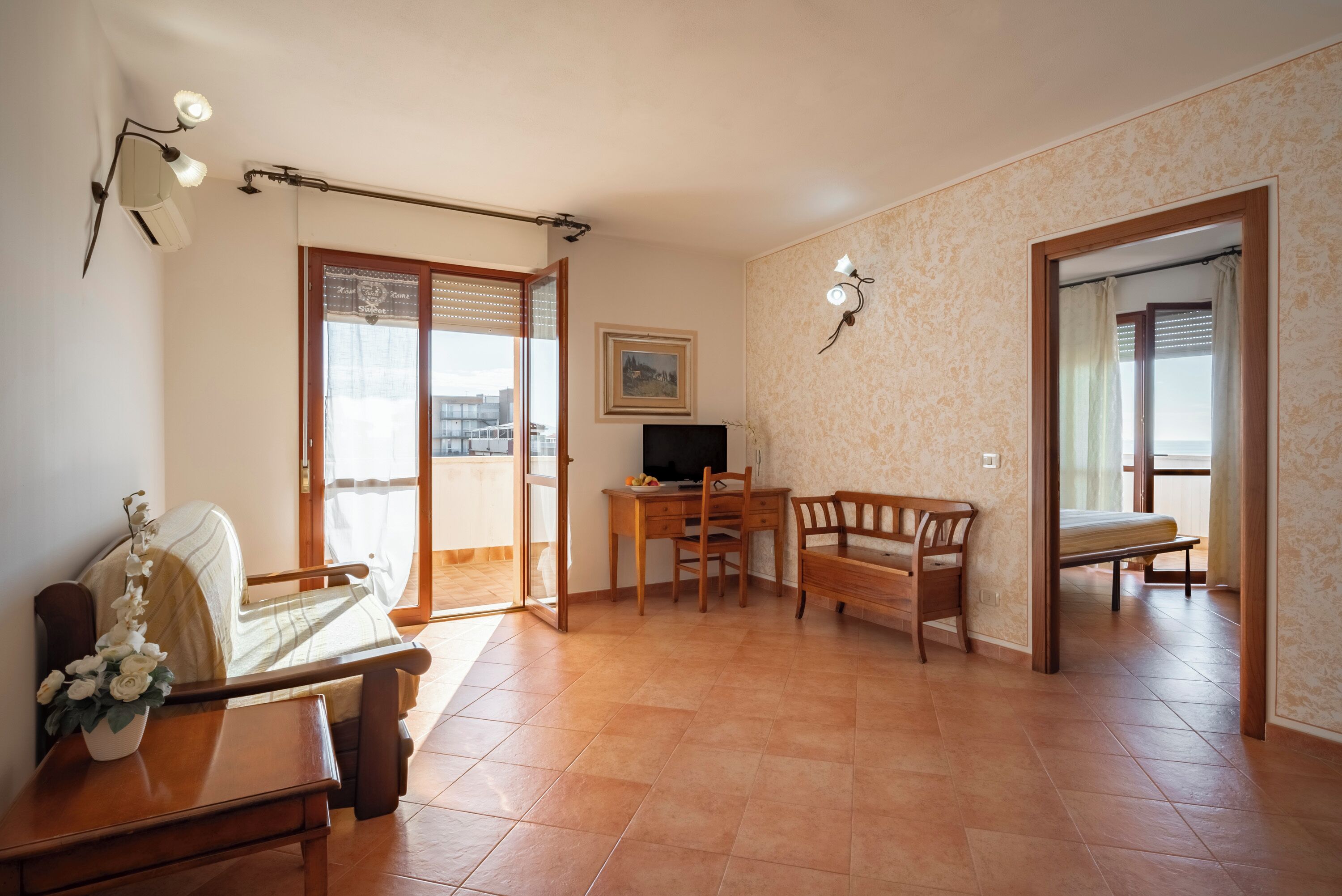 Ampla sala de estar com sofá, mesa de madeira, TV e varanda com vista.