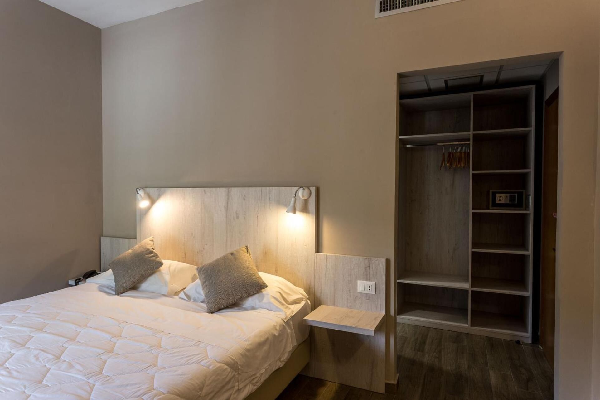 Quarto com cama, abajures, mesa de cabeceira e armário embutido.