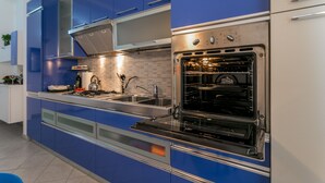 Uma cozinha moderna com armários azuis, eletrodomésticos de aço inoxidável e forno embutido.