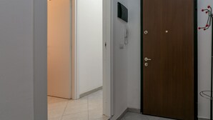 Um corredor com porta de madeira, telefone na parede e luminária.