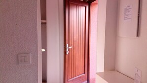Um corredor com uma porta de madeira, um interruptor de luz e uma placa na parede.