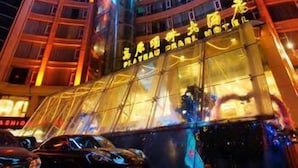 Um hotel de vários andares com uma fachada curva imponente, letreiros iluminados e uma entrada central.