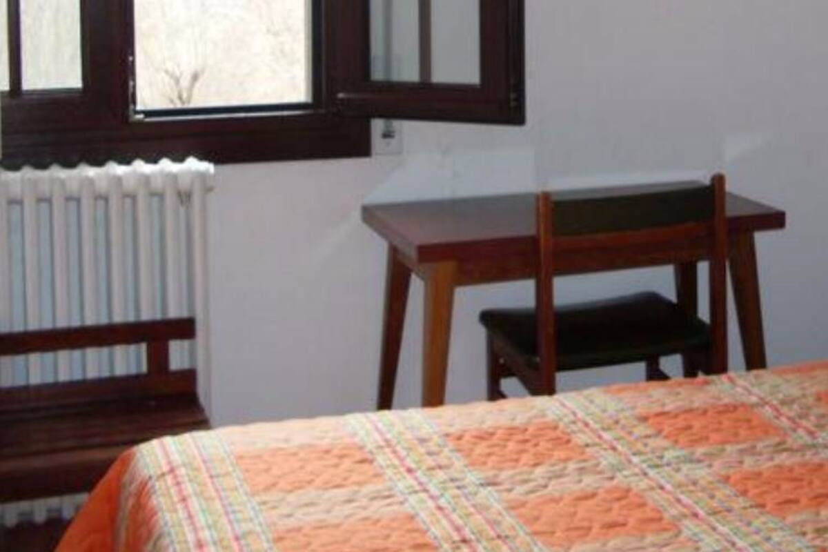 Um quarto com cama, escrivaninha e cadeira.