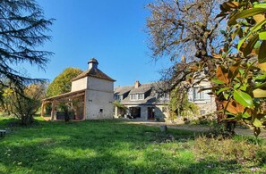 Uma casa no campo com garagem separada, alpendre coberto e um jardim bem cuidado.