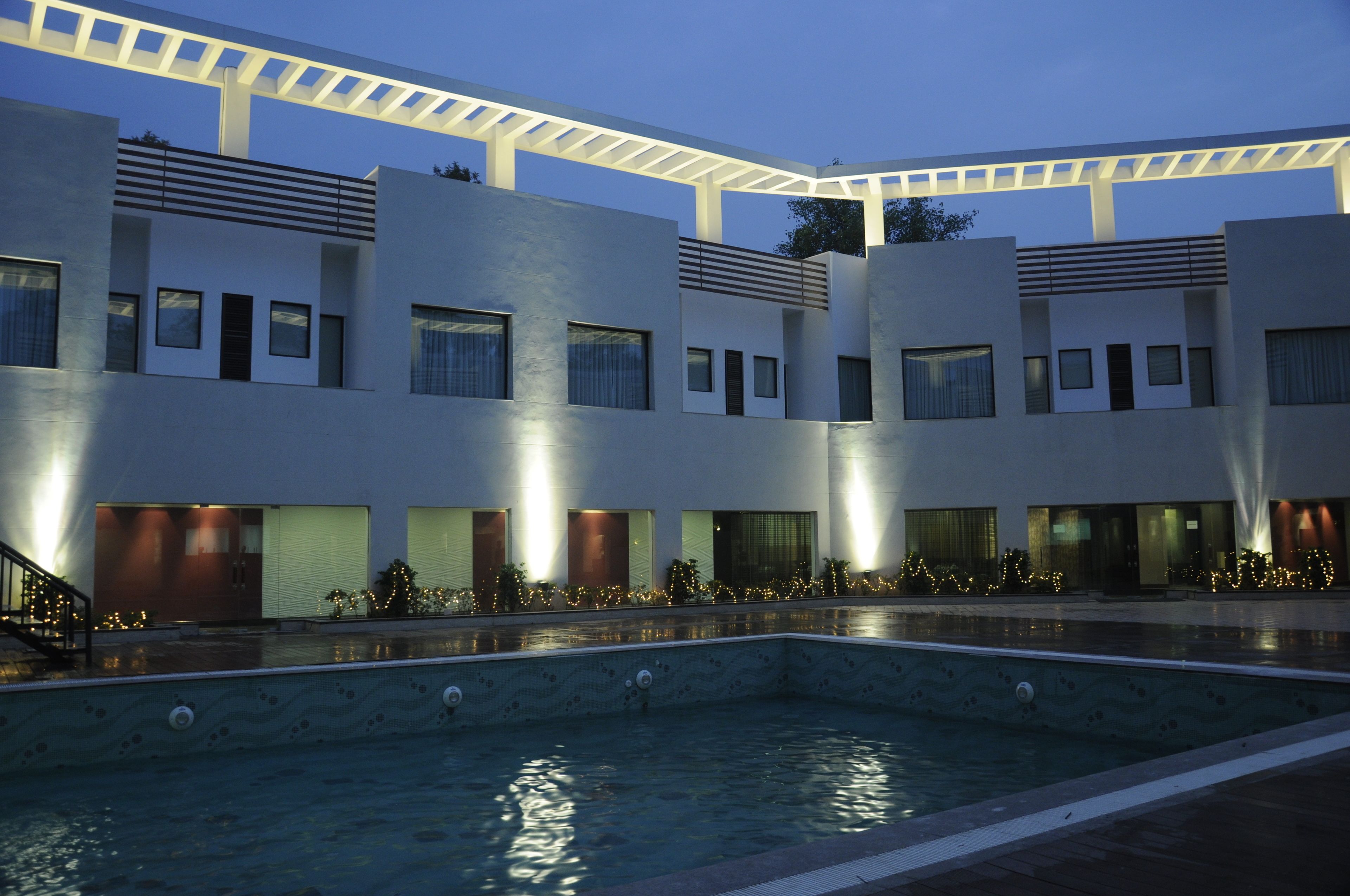 Um edifício moderno com piscina, janelas amplas e área de varanda coberta.