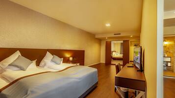 Quarto de hotel com cama grande, mesas de cabeceira, escrivaninha e espelho.