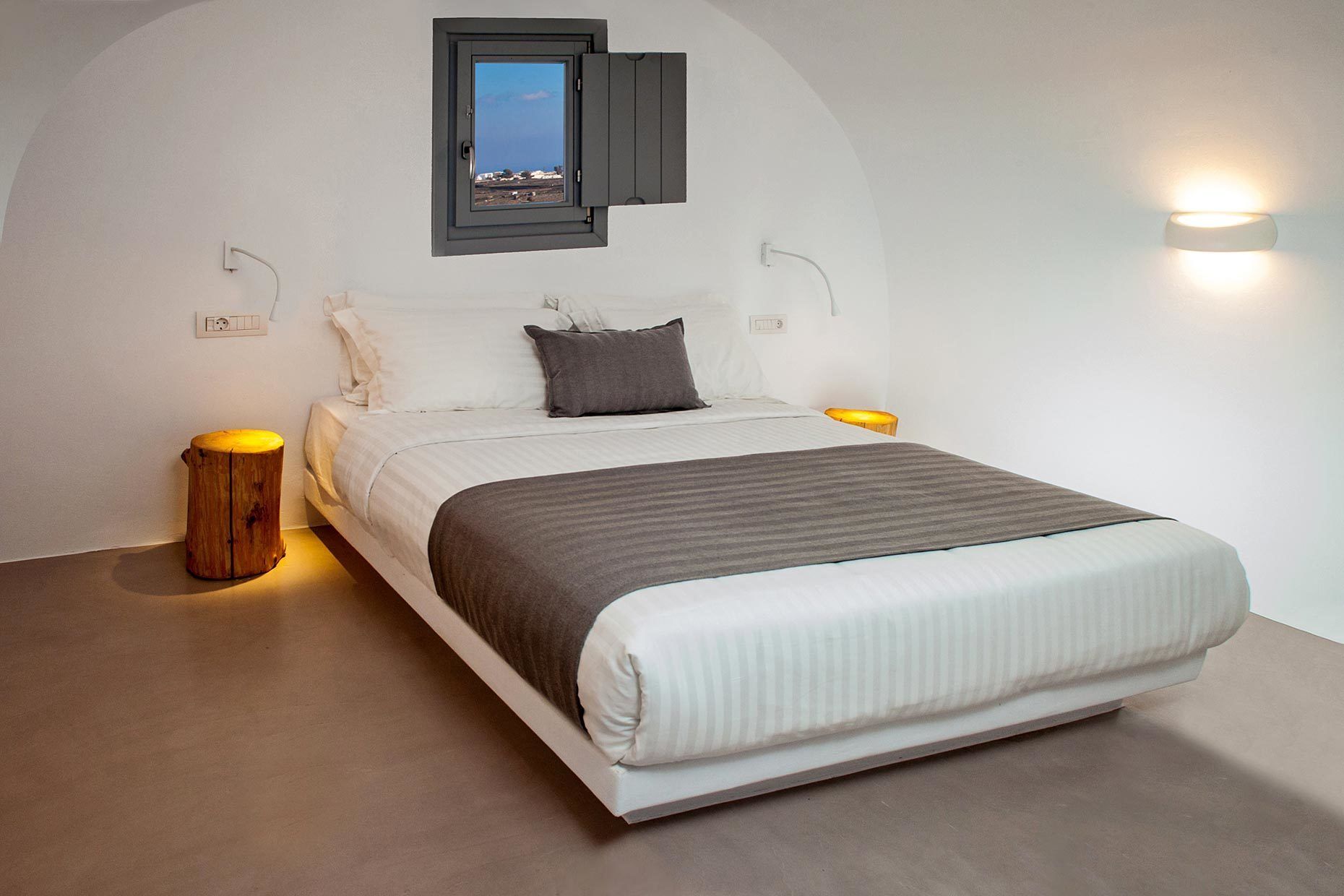 Quarto com cama, janela e duas luminárias de cabeceira.