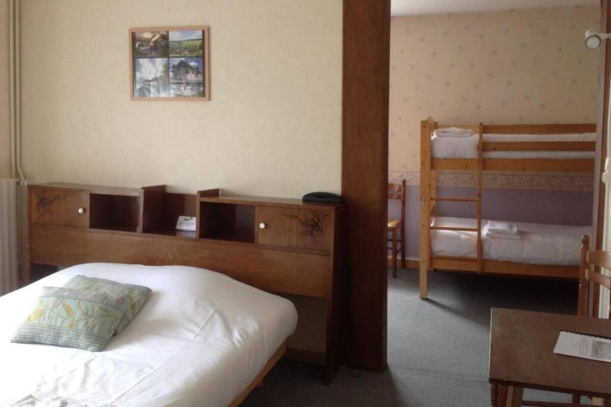 Quarto com uma cama de solteiro, uma escrivaninha de madeira e uma cama beliche.