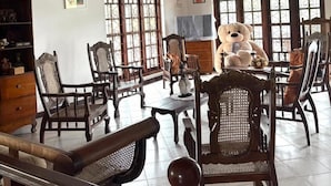 Um quarto espaçoso com vigas de madeira no teto, janelas em arco e um urso de pelúcia grande sobre a mesa de jantar.