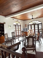 Um quarto espaçoso com vigas de madeira no teto, janelas em arco e um urso de pelúcia grande sobre a mesa de jantar.