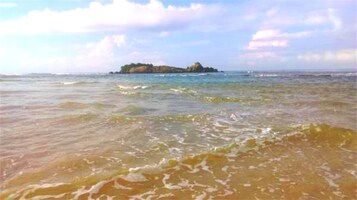 Uma praia com água cristalina e uma pequena ilha ao longe.