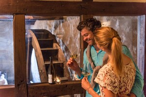 Interior em madeira com uma escada rústica e uma garrafa de vinho sobre uma mesa.