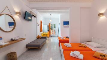 Quarto de hotel moderno com duas camas, um sofá, uma televisão e um espelho.