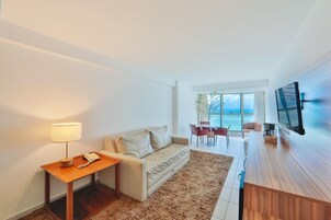 Uma sala de estar moderna com sofá, mesa de centro, abajur e TV na parede.