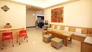 Uma sala de estar moderna com um sofá de madeira, uma mesa de jantar e duas cadeiras vermelhas.
