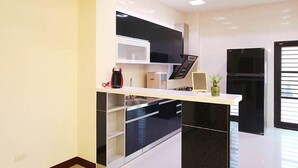 Uma cozinha moderna com armários preto e branco, uma ilha central e uma luminária pendente.