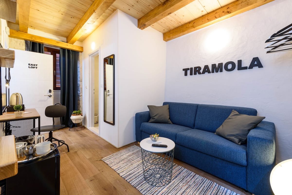 Uma sala de estar moderna com um sofá azul, uma mesa de centro e uma televisão fixada na parede.