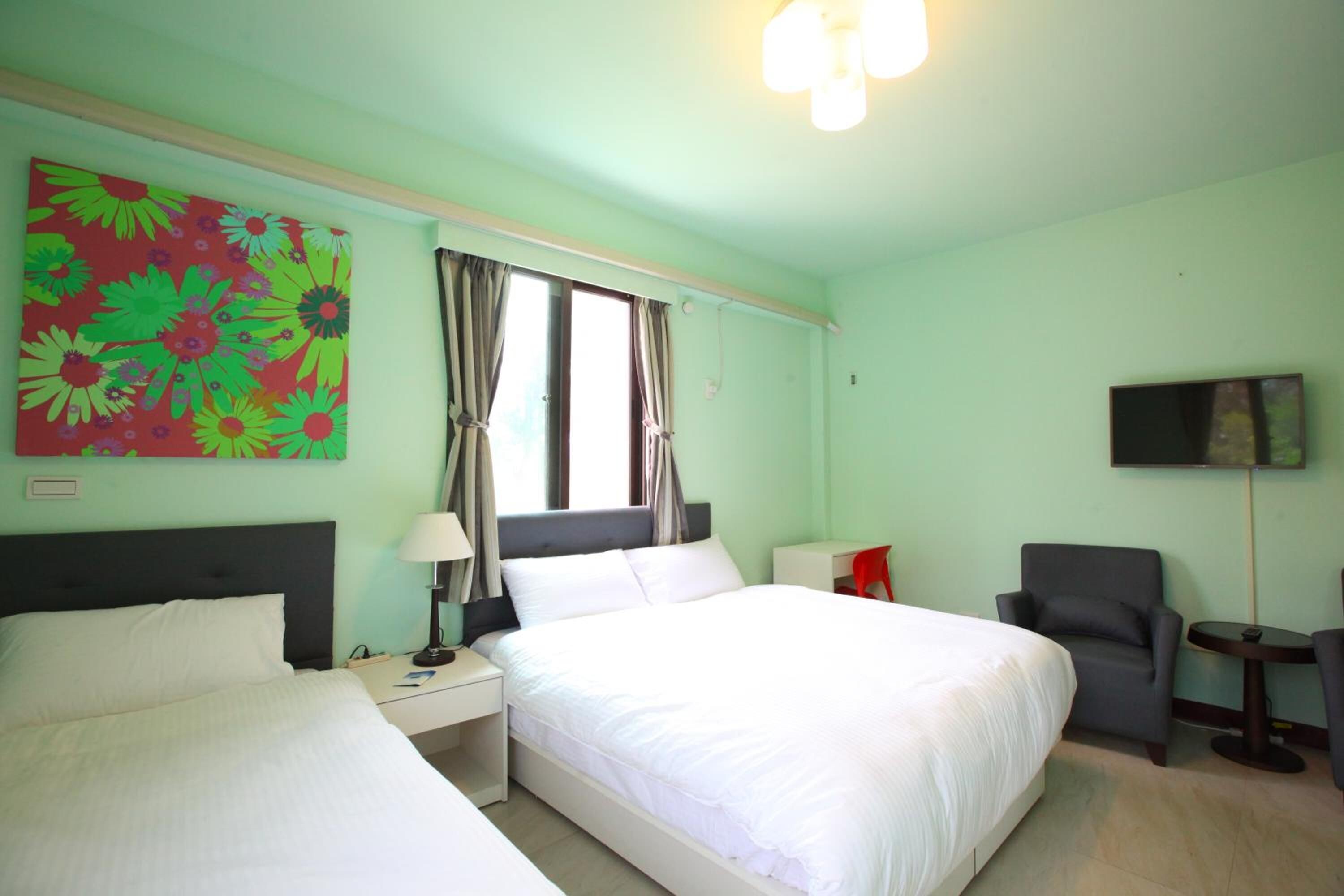 Quarto de hotel com uma cama grande, uma mesa, uma cadeira e uma TV na parede.