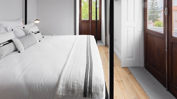 Quarto com uma cama, luminária pendente e vista por uma porta.