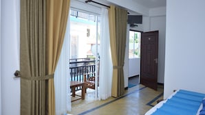 Quarto com cama, varanda com guarda-corpo e porta que dá para outro cômodo.