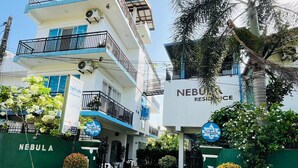 Um edifício residencial com várias andares, varandas, entrada com portão e um jardim bem cuidado.