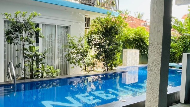 Piscina com água cristalina azul, rodeada por espreguiçadeiras e plantas em vasos.