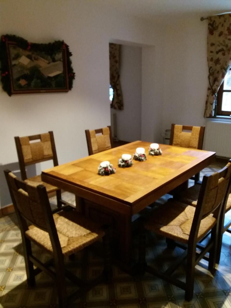 Uma sala de jantar com uma mesa de madeira e seis cadeiras, cada uma com almofada.