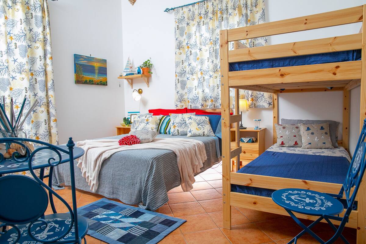 Um quarto acolhedor com uma cama de solteiro, uma escrivaninha, uma cadeira e uma pequena mesa.