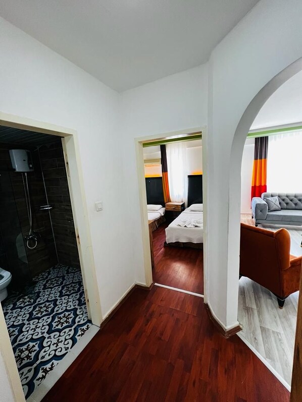 Quarto de hotel com chuveiro, duas camas, um sofá e vista para a cidade.