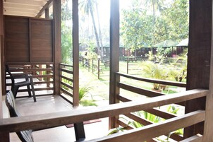 Um deck de madeira com bancos, cercado por vegetação exuberante e vista para um jardim tropical.