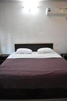 Uma cama de solteiro com cabeceira, mesa de cabeceira e ar condicionado fixado na parede.