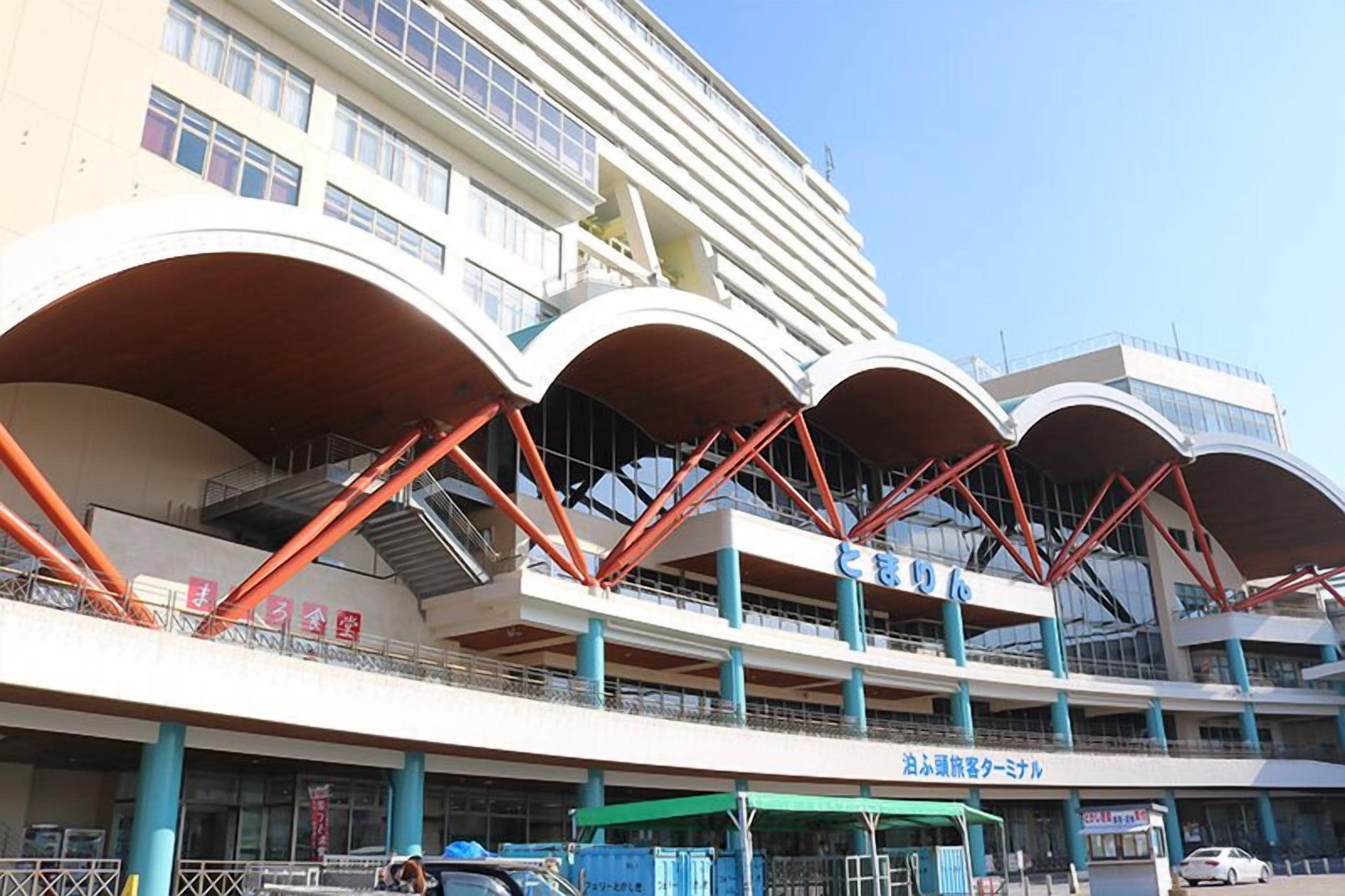 Edifício de vários andares com design arquitetônico marcante, com telhados curvos sustentados por vigas de metal vermelhas.