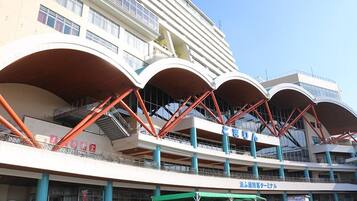 Edifício de vários andares com design arquitetônico marcante, com telhados curvos sustentados por vigas de metal vermelhas.