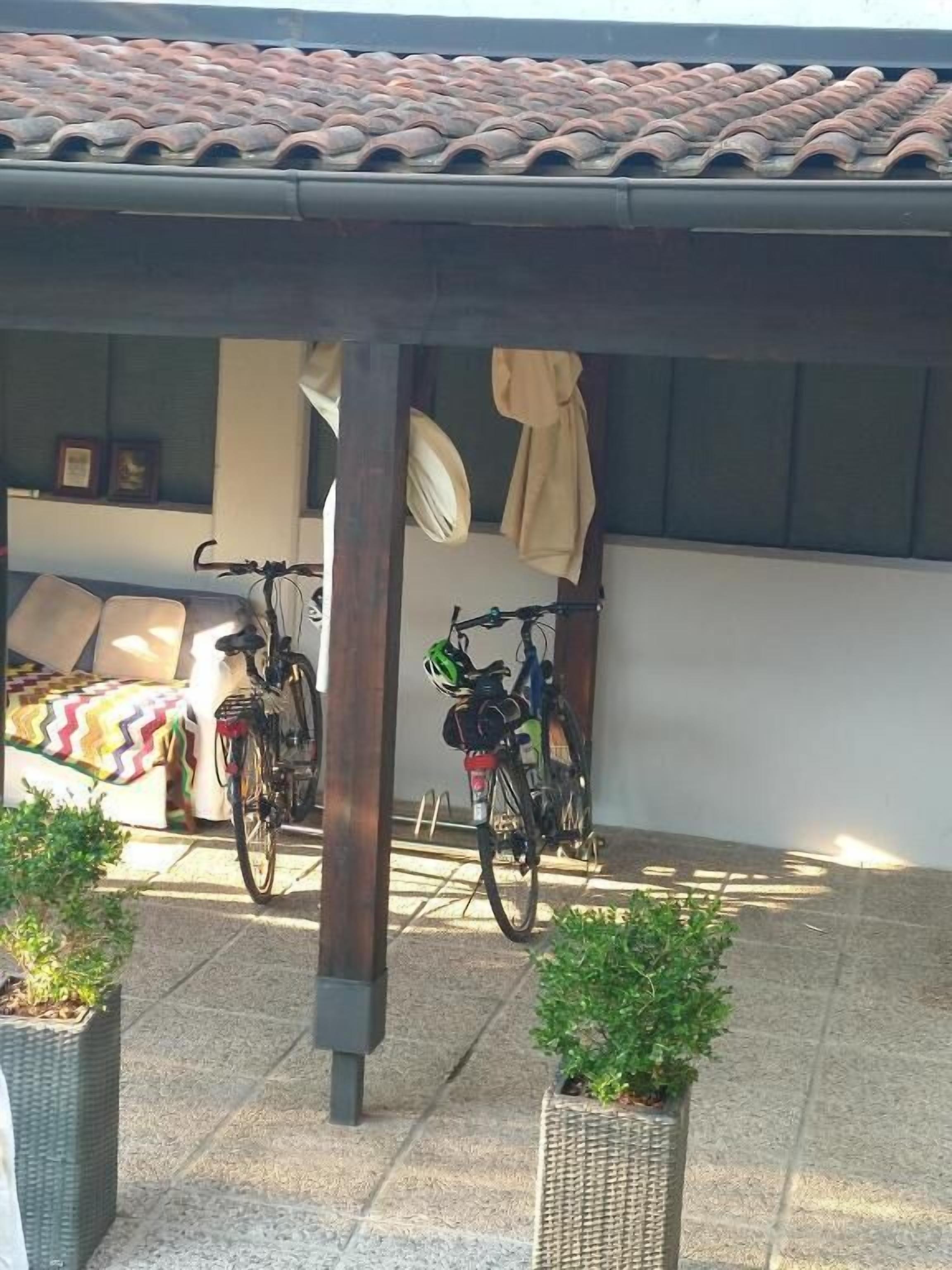 Espaço ao ar livre coberto com telhado de azulejos, bicicletas e plantas em vasos.