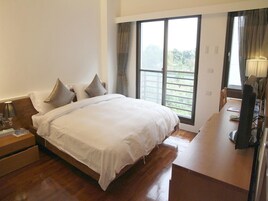 Quarto com uma cama grande, uma escrivaninha e uma televisão.