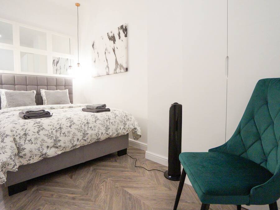 Quarto com cama, uma cadeira e uma obra de arte na parede.