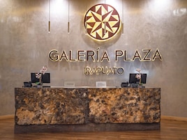 Um balcão de recepção com bancada de mármore, um logotipo acima e a inscrição "GALERÍA PLAZA IRAPUATO".