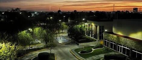 Uma área de estacionamento ampla com um design circular central, rodeada por vegetação e edifícios modernos.